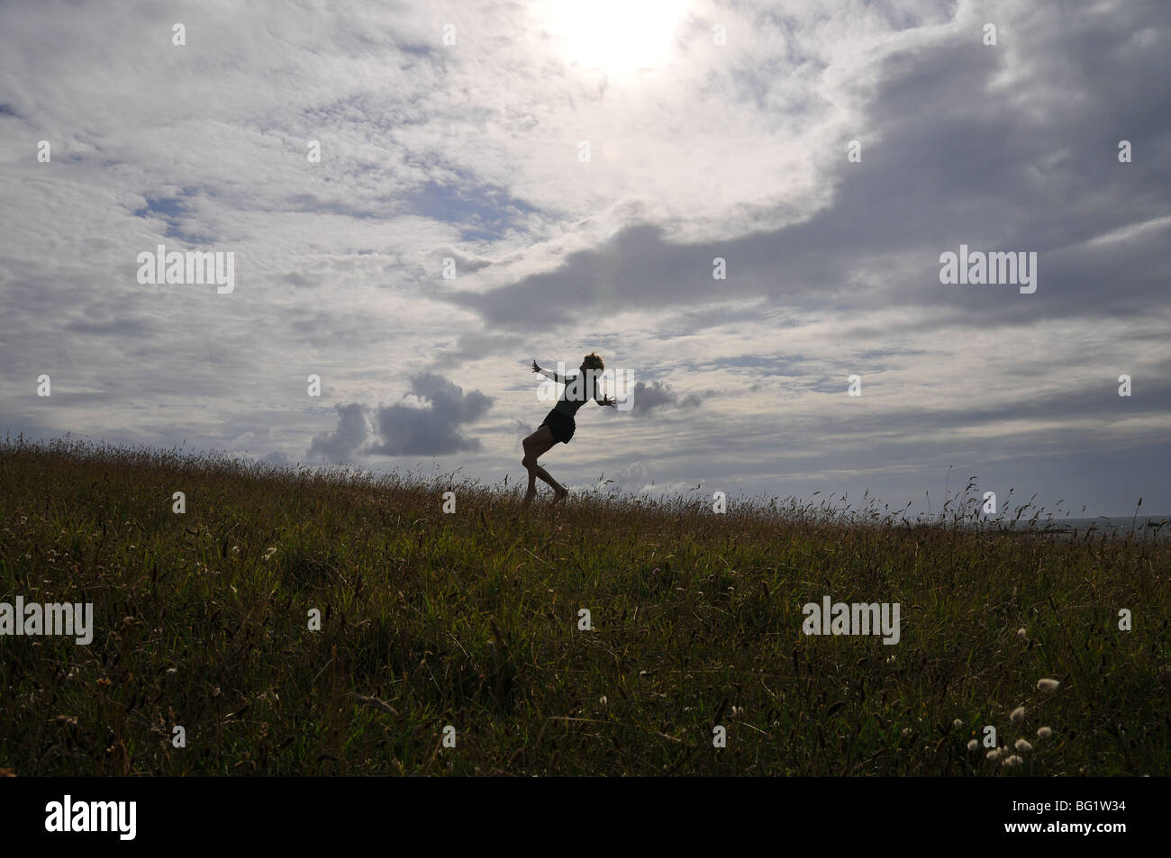 young white woman jumping and leaping on the dune arms up imbalanced ...