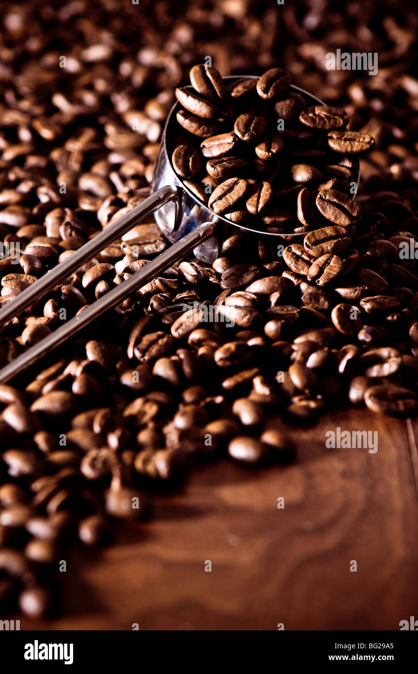 Ladle of coffee beans on mahogany table - high contrast Stock Photo - Alamy