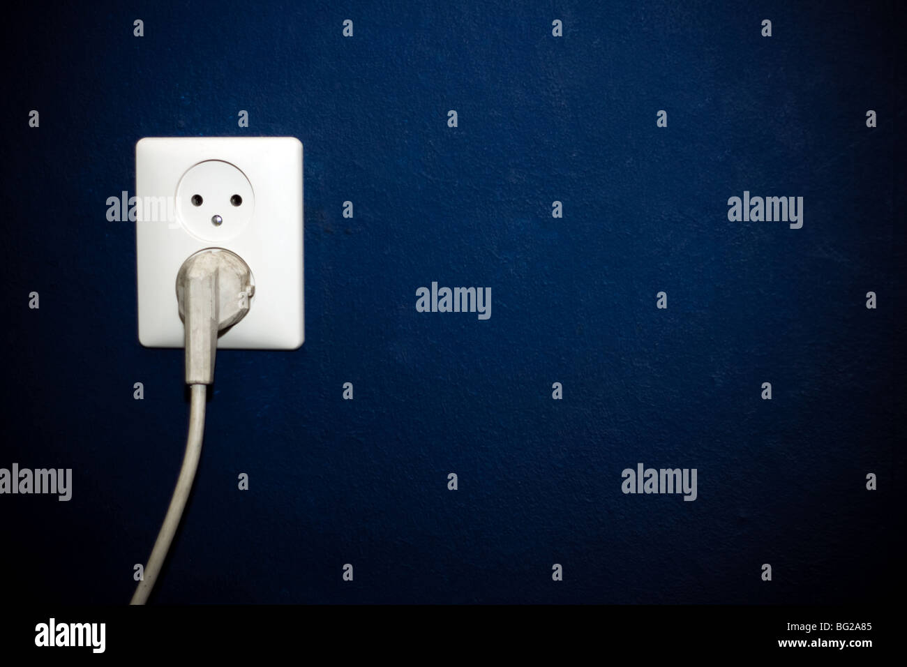 White socket with one old plug in dark blue wall Stock Photo - Alamy