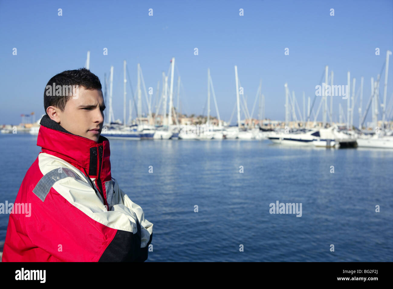 Handsome boy on blue marina harbor with red marine coat Stock Photo - Alamy