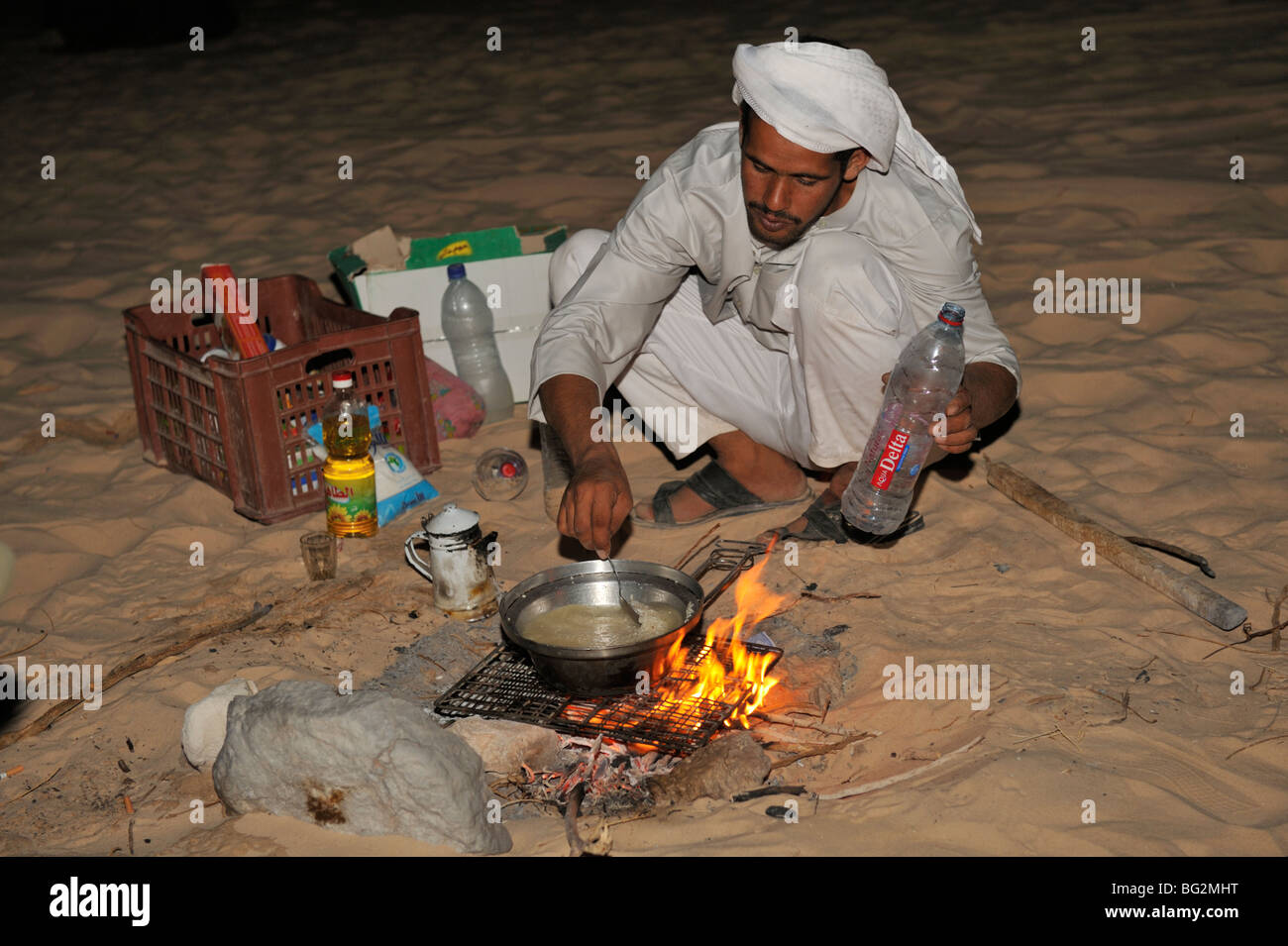 Bedouin men cooking meal in the desert over fire at night on desert ...