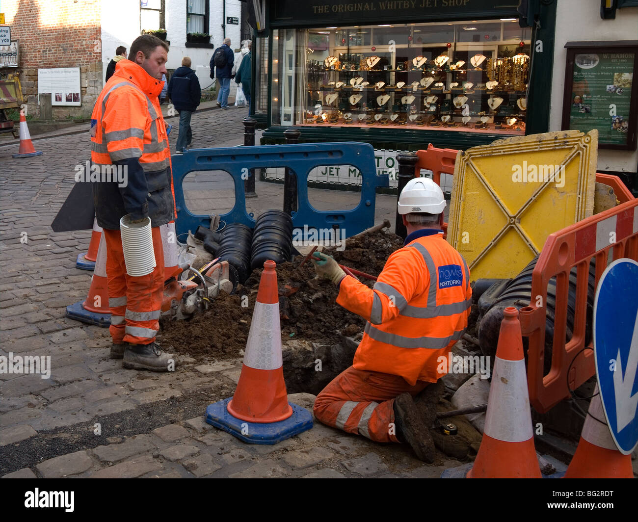 Drainage contractor workmen refitting drains in a narrow street in ...