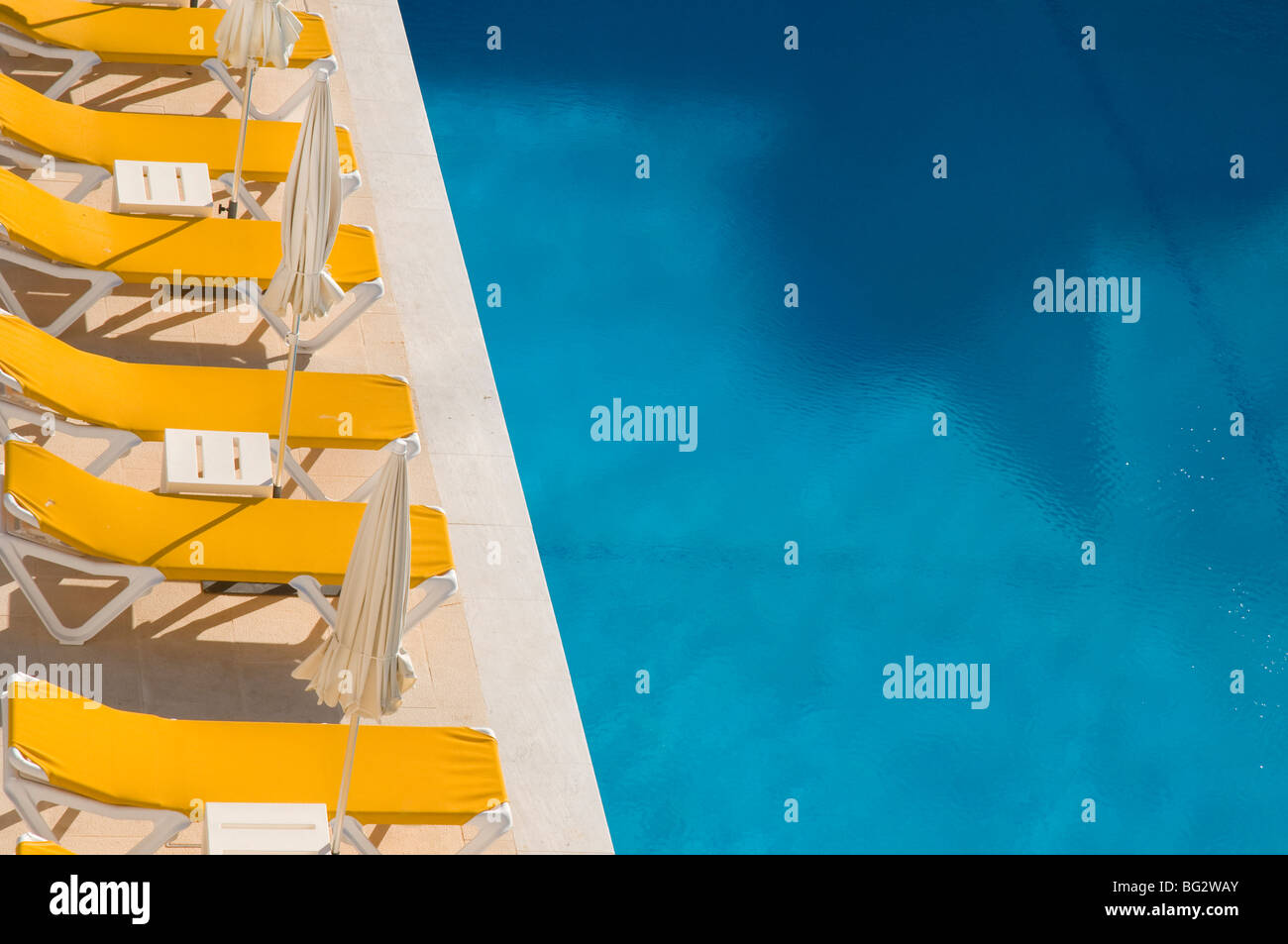 Yellow Sun lounges next to Swimming Pool Stock Photo - Alamy