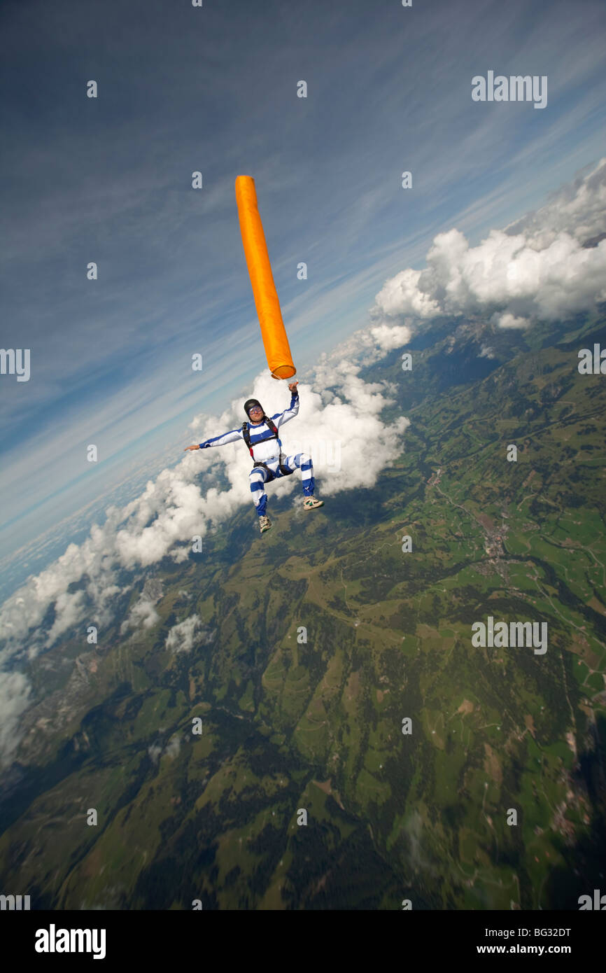 Skydiver with orange tube is flying over a nice mountain scenery. The ...