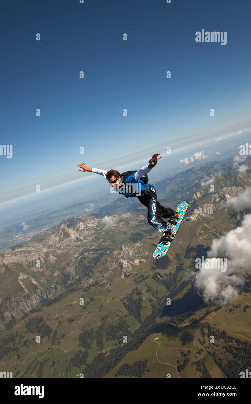 Skydiver is surfing on his sky board over mountain area, passing clouds ...