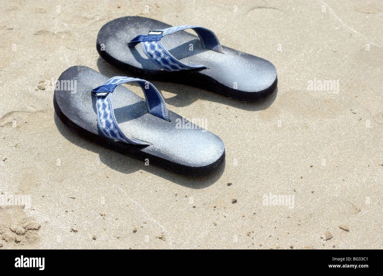 Royalty free photograph of a pair of flip flops on a beach in the sand ...