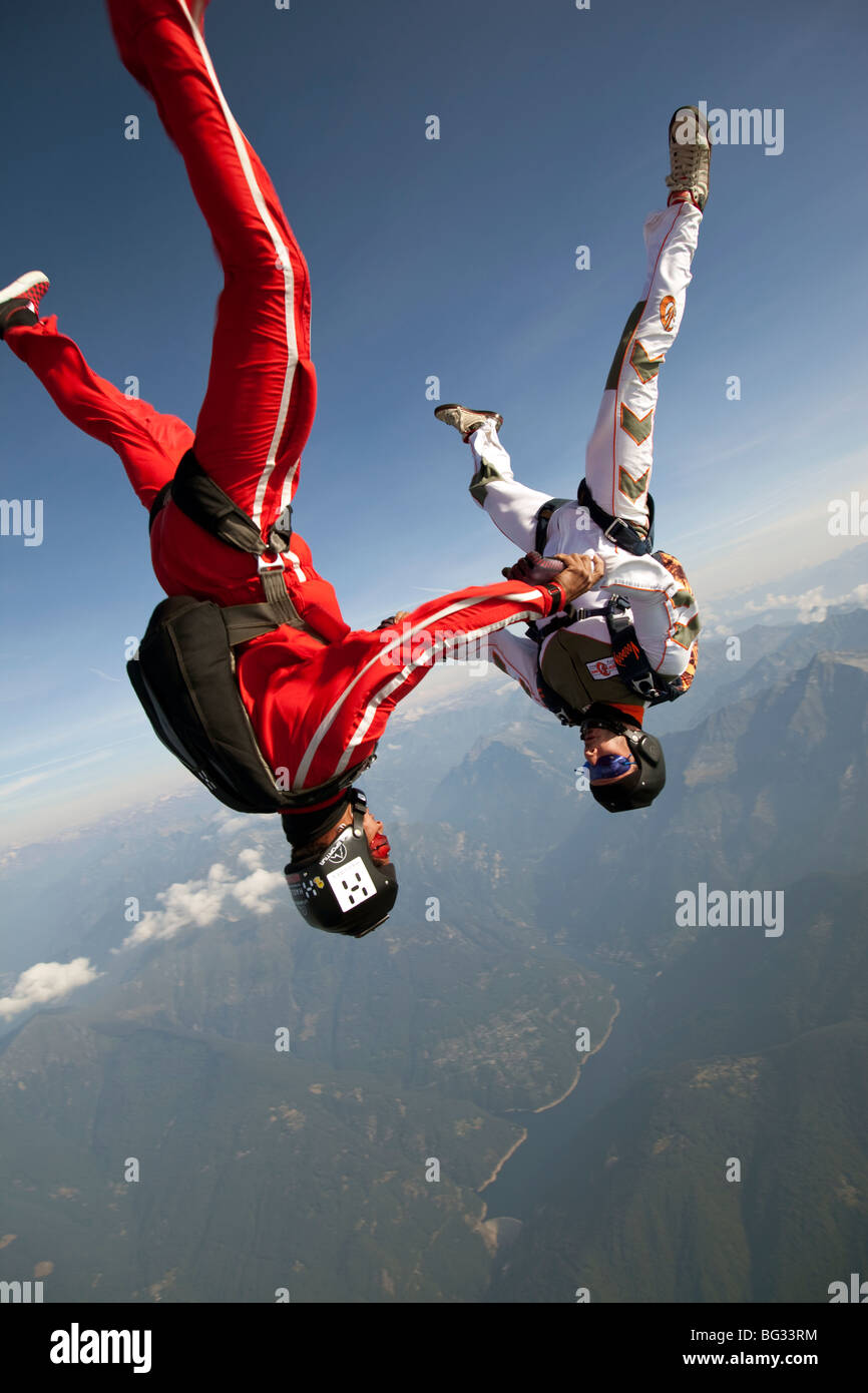 Skydivers are flying head down and holding each other. In this freefly ...