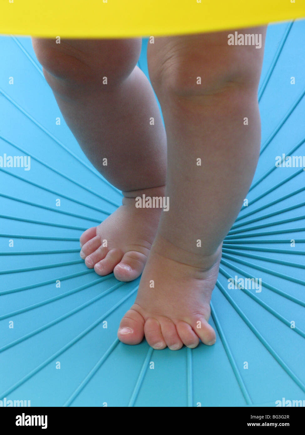 Legs and feet of an infant learning to walk in a blue environment Stock ...