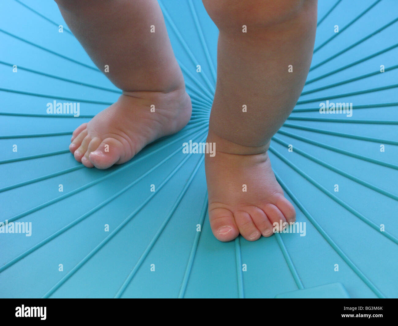 Legs and feet of an infant learning to walk in a blue environment Stock ...