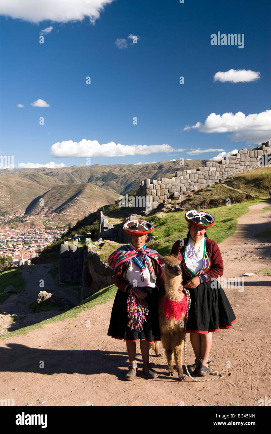 Inca women in traditional dress and llama, with the fortress of ...