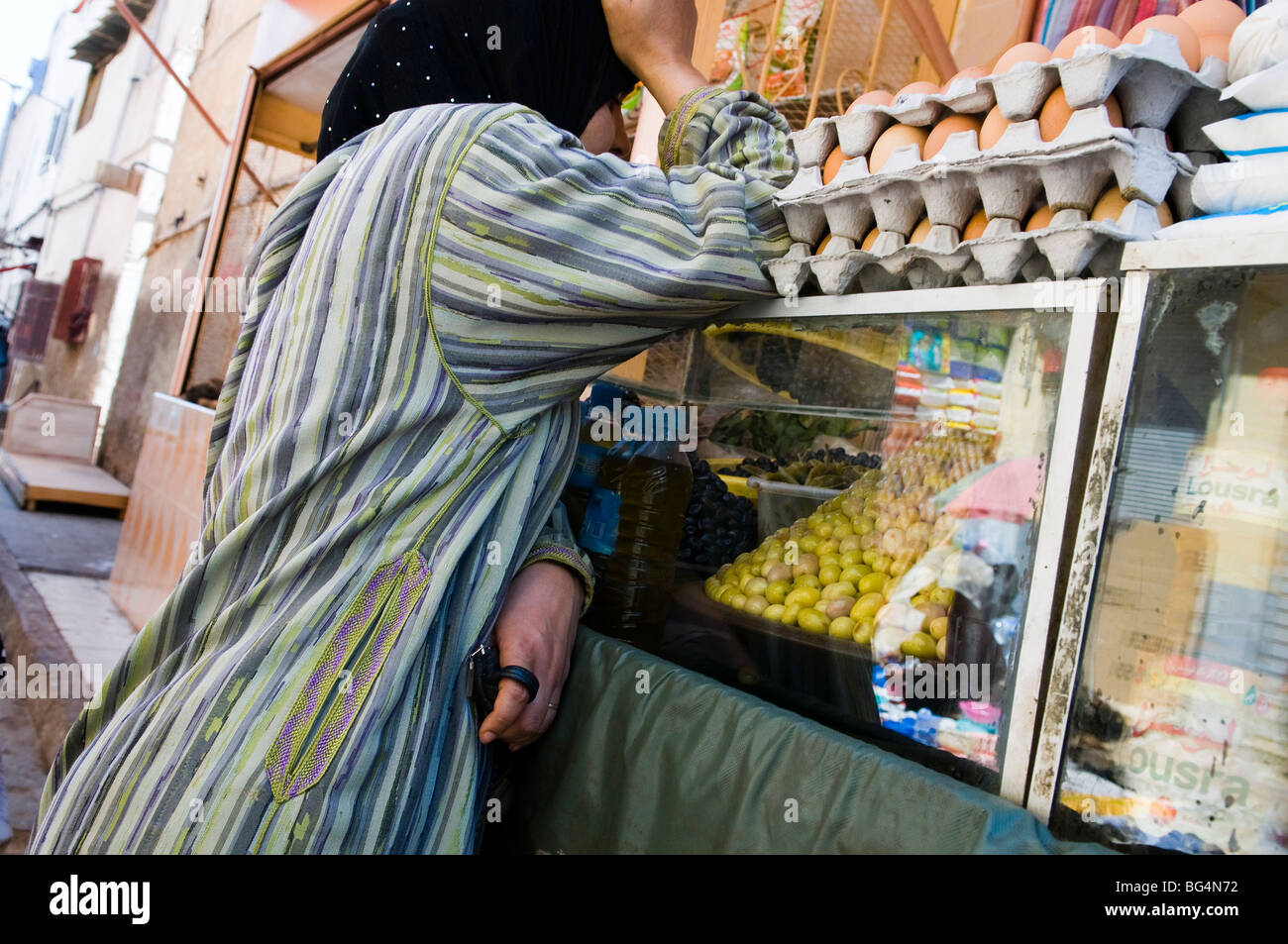 A Moroccan woman dressed in a traditional Jalaba shops in a local ...