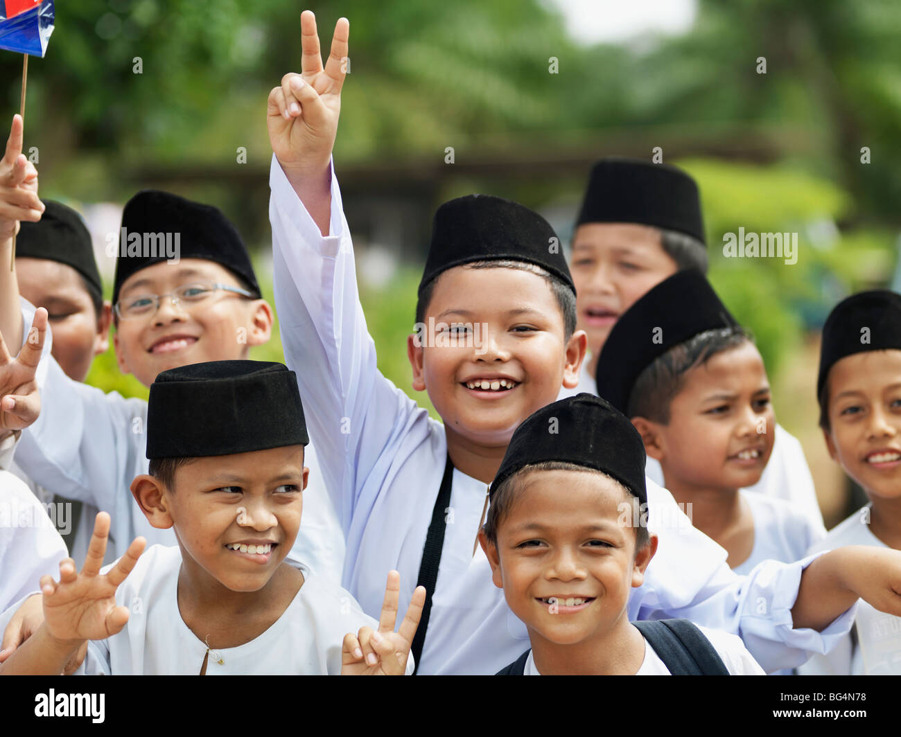 A group of young Muslim boys waving hello and holding up in the "Peace ...