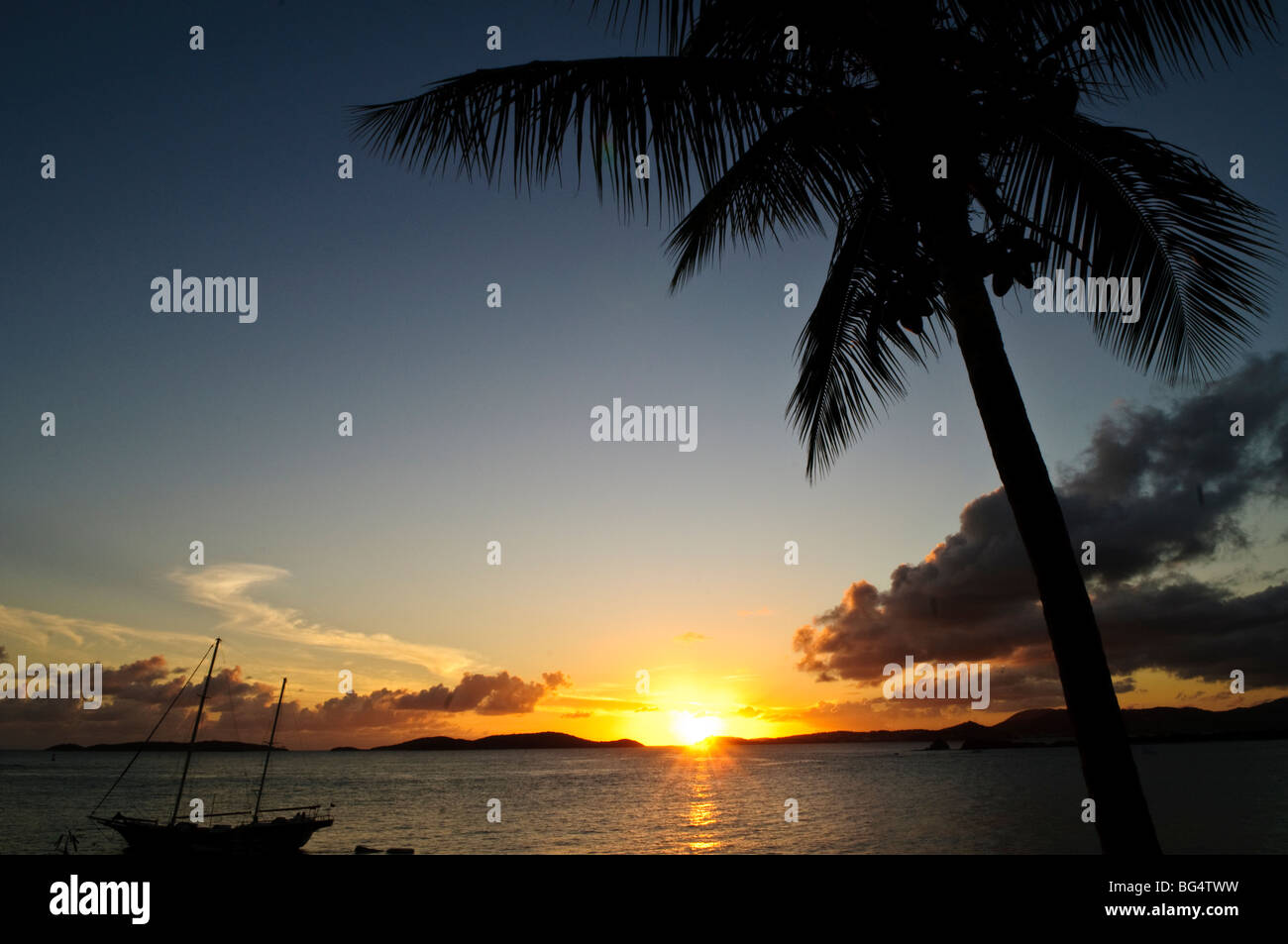 A beautiful sunset in the Caribbean with a palm tree and sailing boat ...