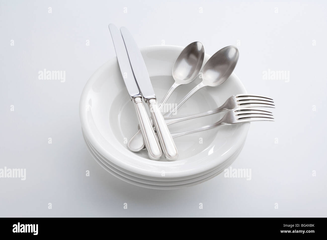 white plates with silverware isolated on white Stock Photo - Alamy