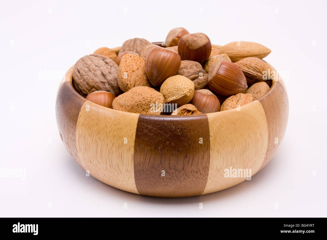 wooden bowl filled with mixed nuts in their shells, hazelnuts, walnuts ...