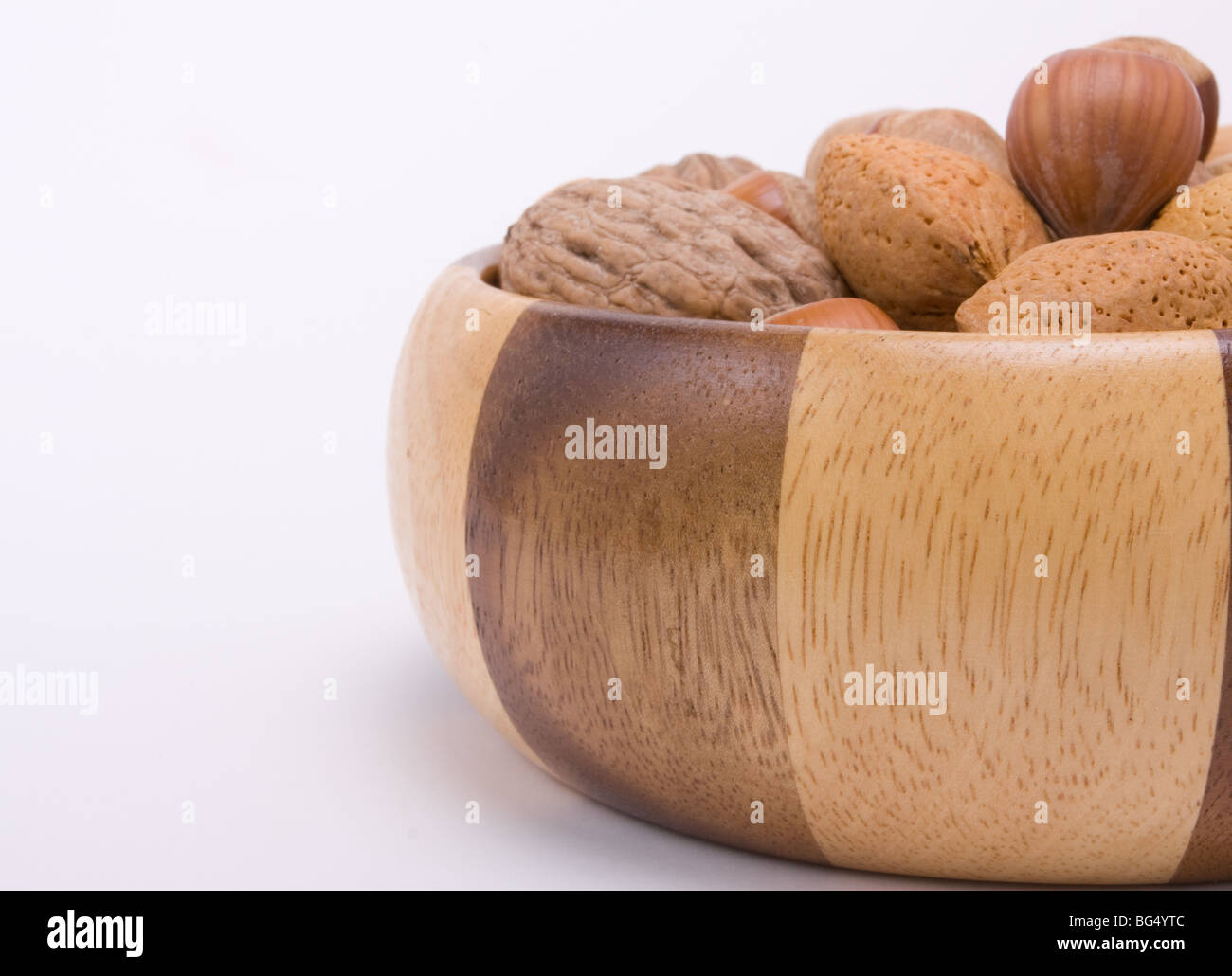 wooden bowl filled with mixed nuts in their shells, hazelnuts, walnuts ...