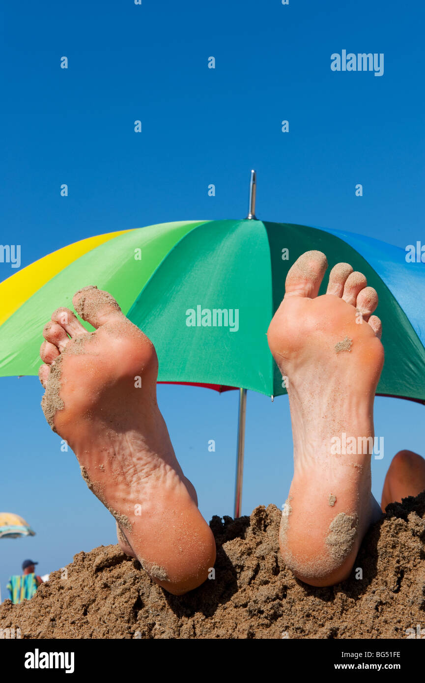 beach vacation in the summer with bare feet and parasol in the sand ...