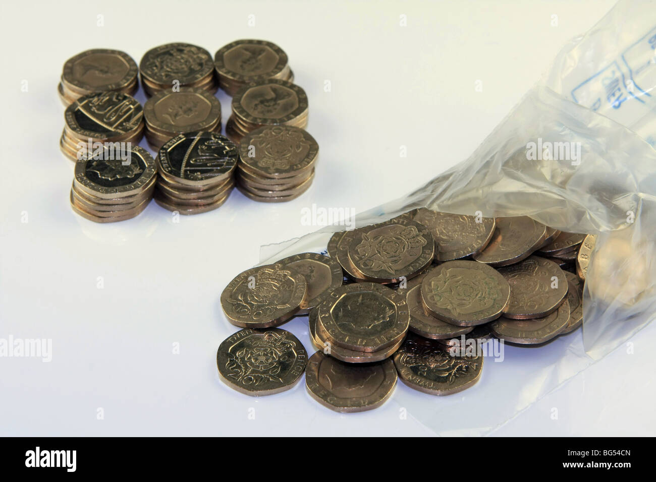 stacks of 20p coins next to an open coin bag with 20p coins protruding ...