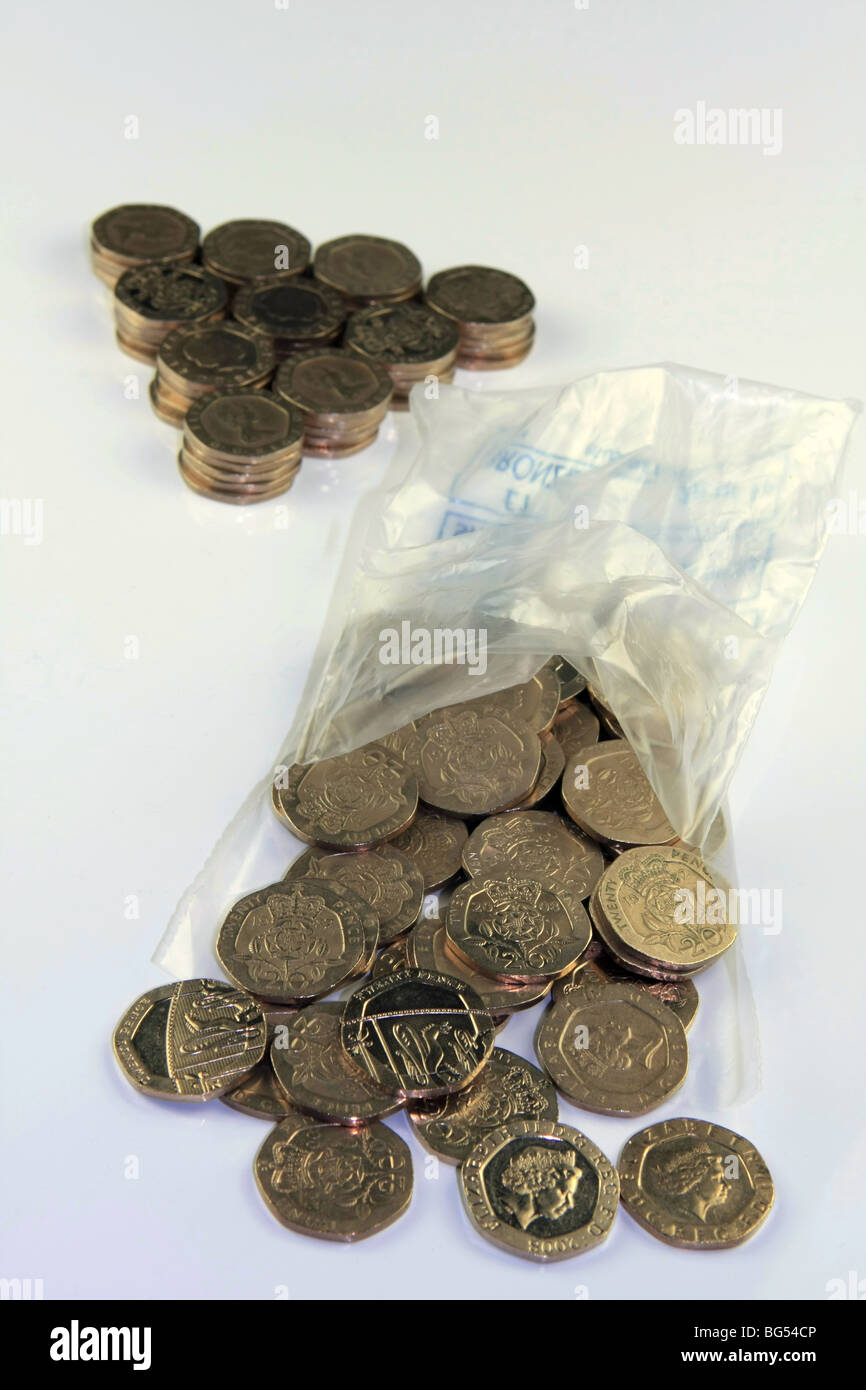 stacks of 20p coins next to an open coin bag with 20p coins protruding ...