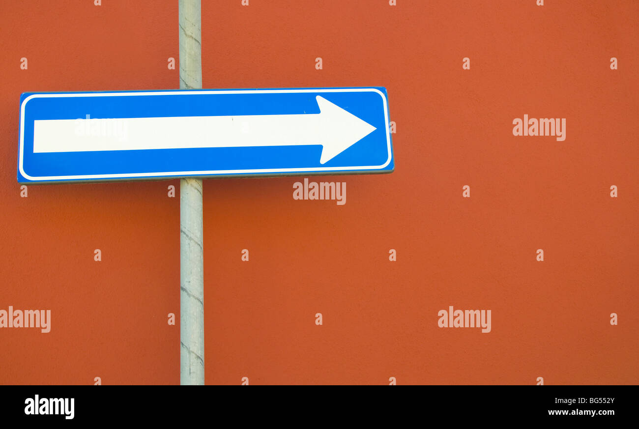 Blue directional sign against a terracotta wall Stock Photo - Alamy