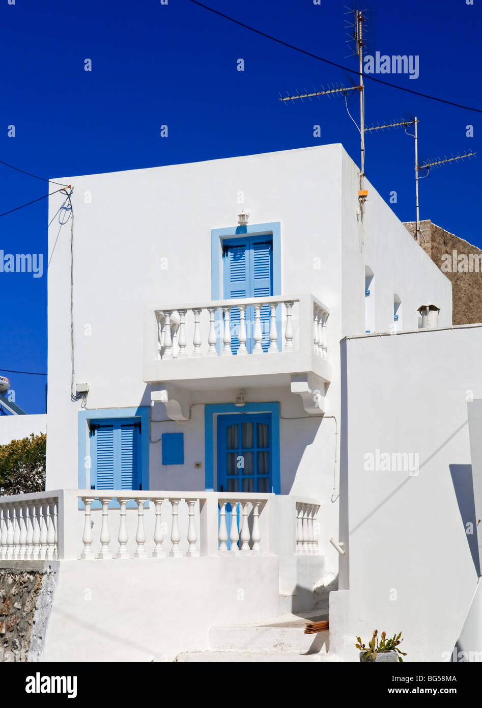 Typical Greek house with white painted walls and blue shuttered windows ...