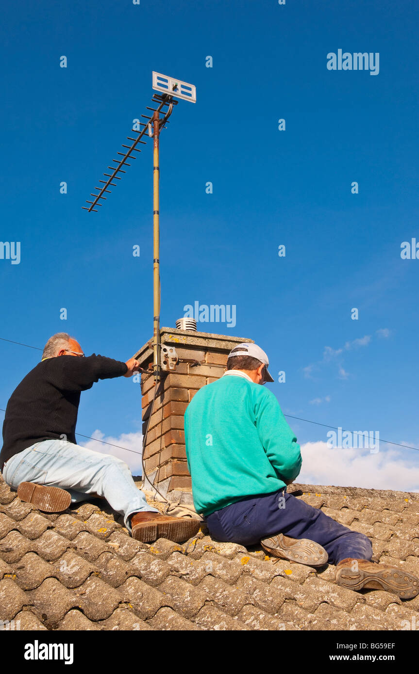 Two builders re-pointing a chimney (raking out the cement joints and ...