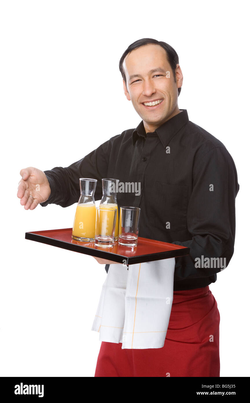 Male waiter smiling and pouring orange juice Stock Photo - Alamy