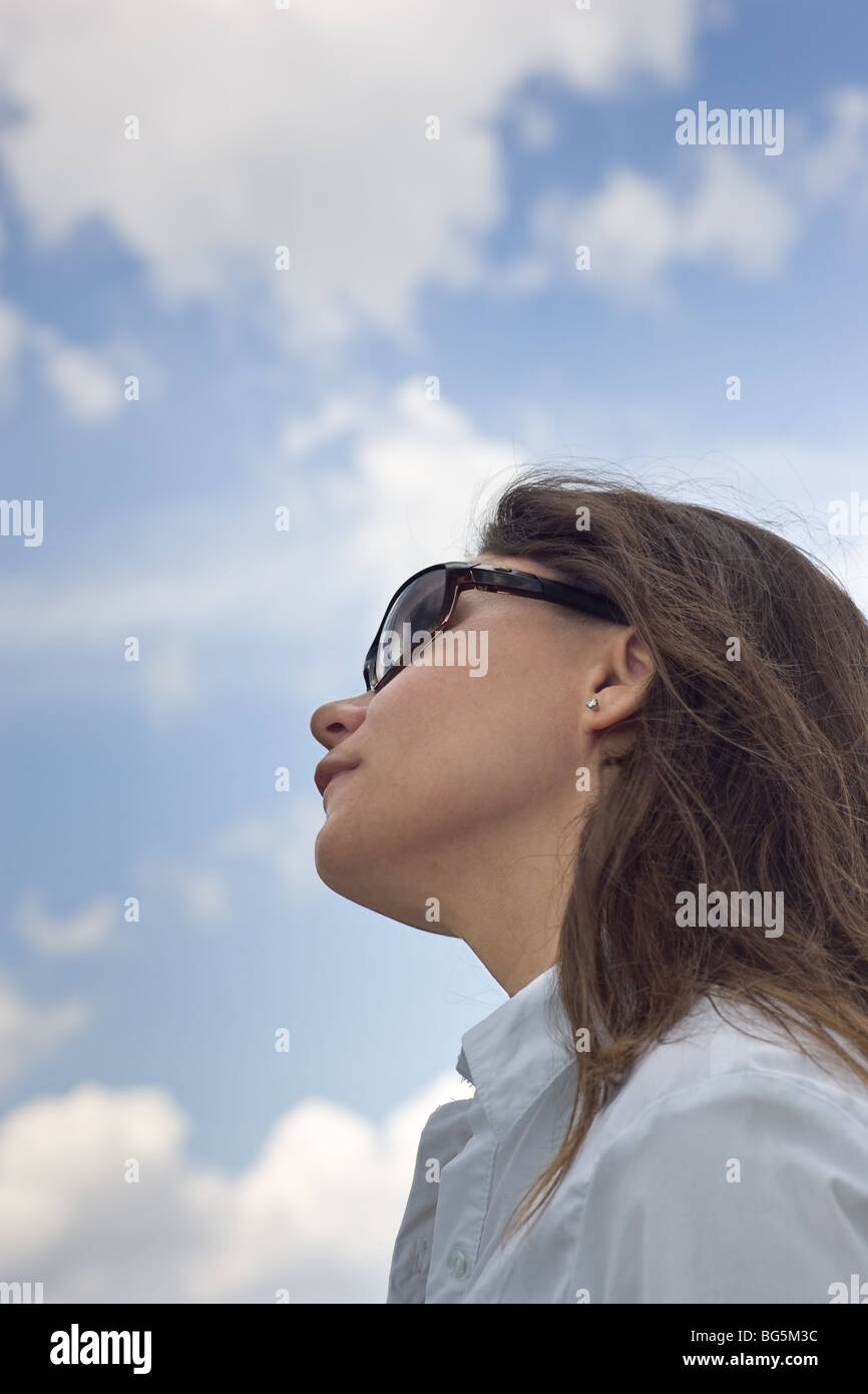 Looking up at a womans face, as she looks up to the sky, with a blue ...