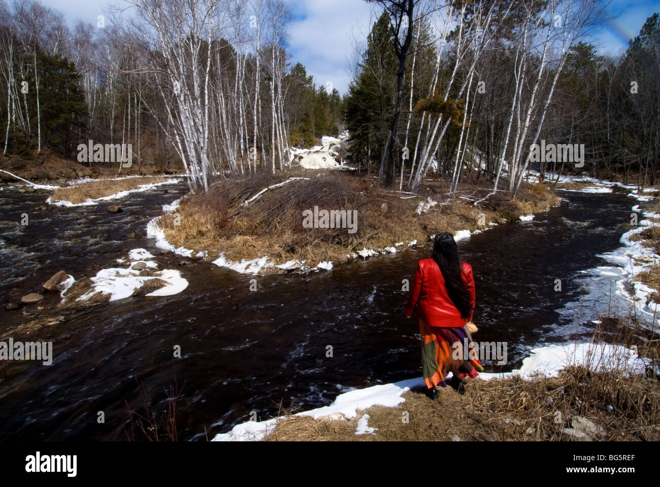 Native Indian woman standing alongside rushing river waters downstream ...