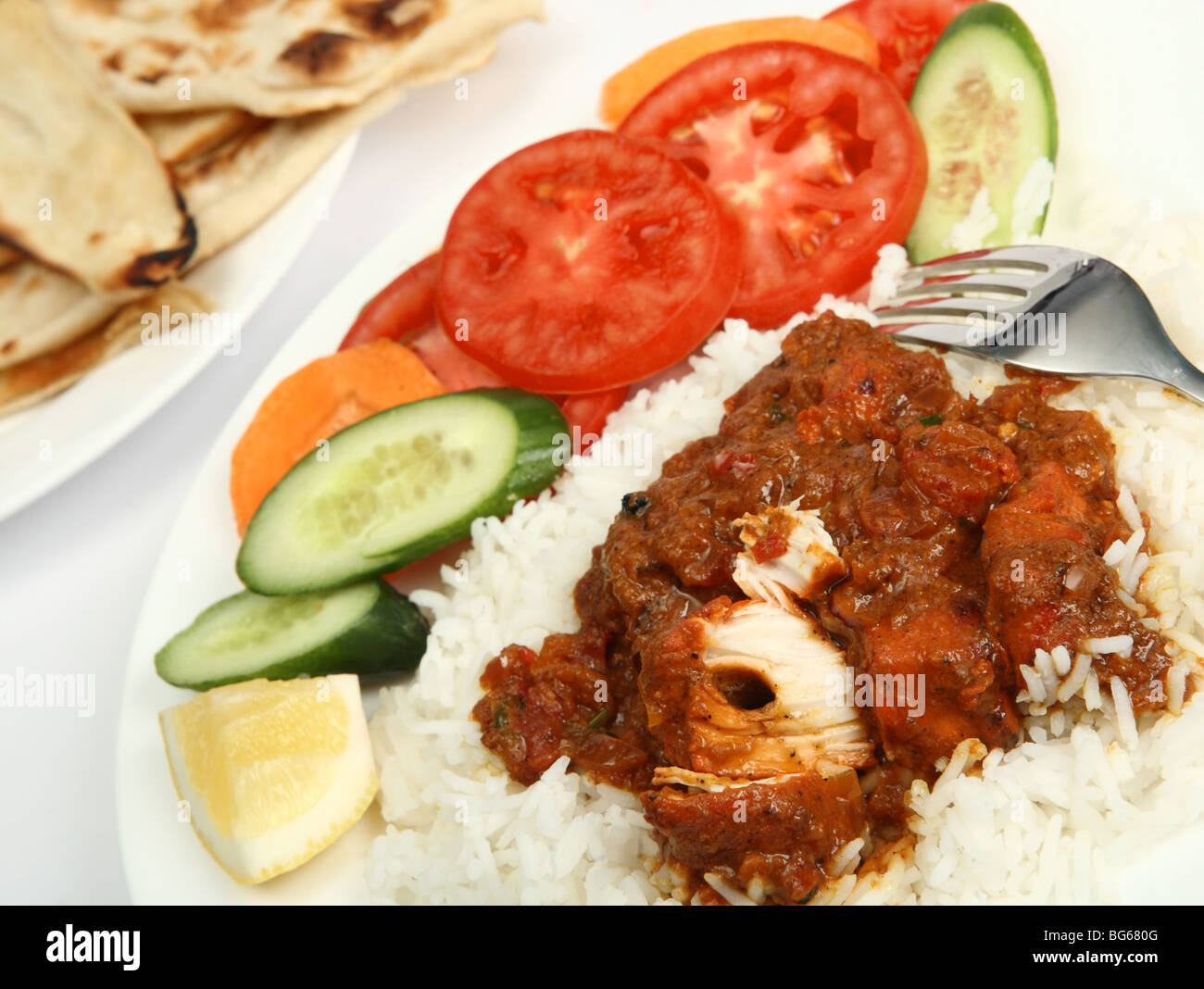 a plate of chicken tikka masala, served with white rice, a side salad ...