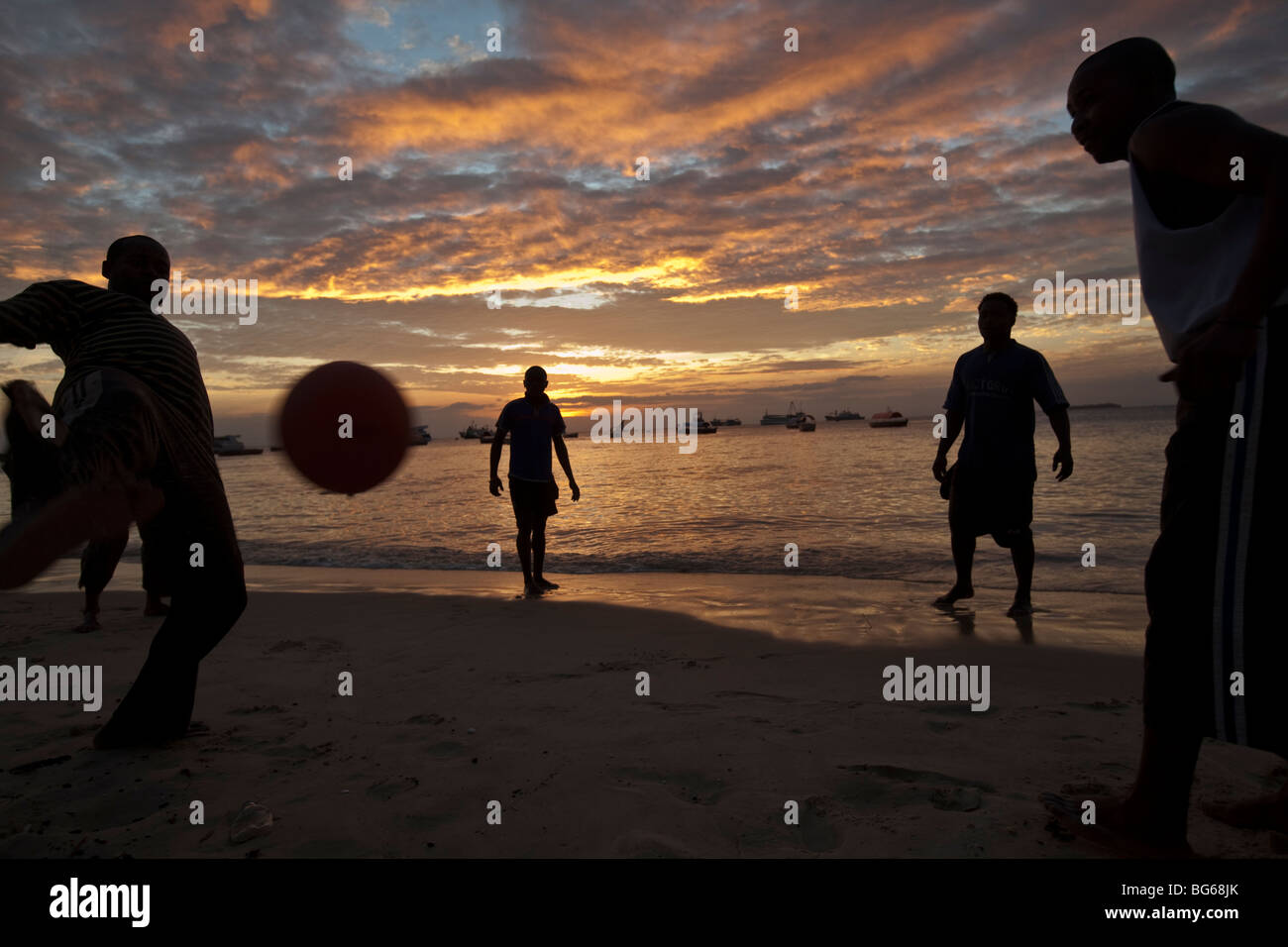 Youths play football at sunset along the shores of the Indian Ocean in ...