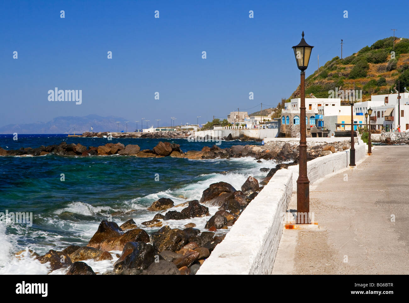 View of houses and promenade on coastline at Mandraki on the Greek ...