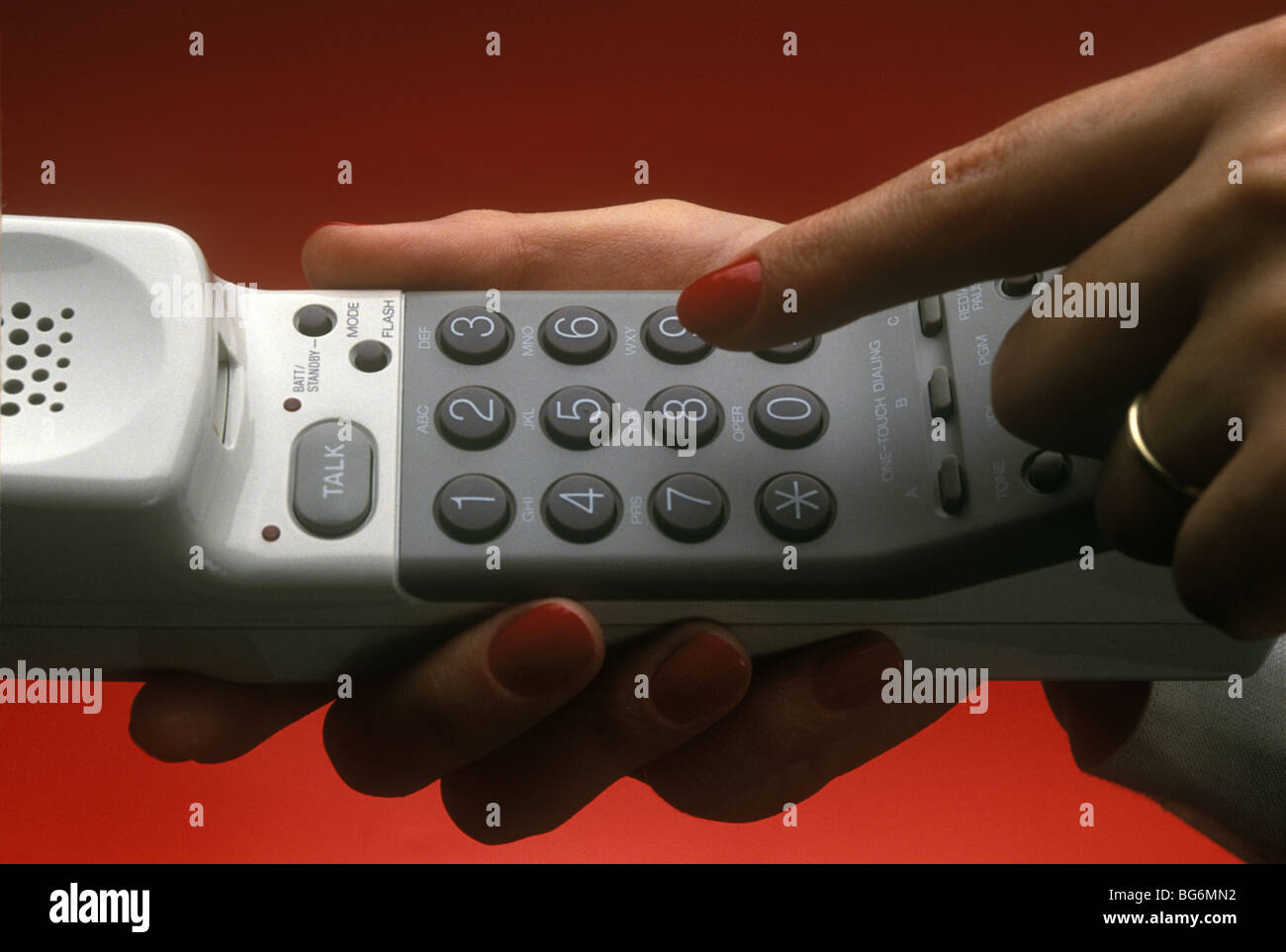 WOMANS HAND DIALING TELEPHONE KEYPAD ON PLAIN RED BACKGROUND Stock ...