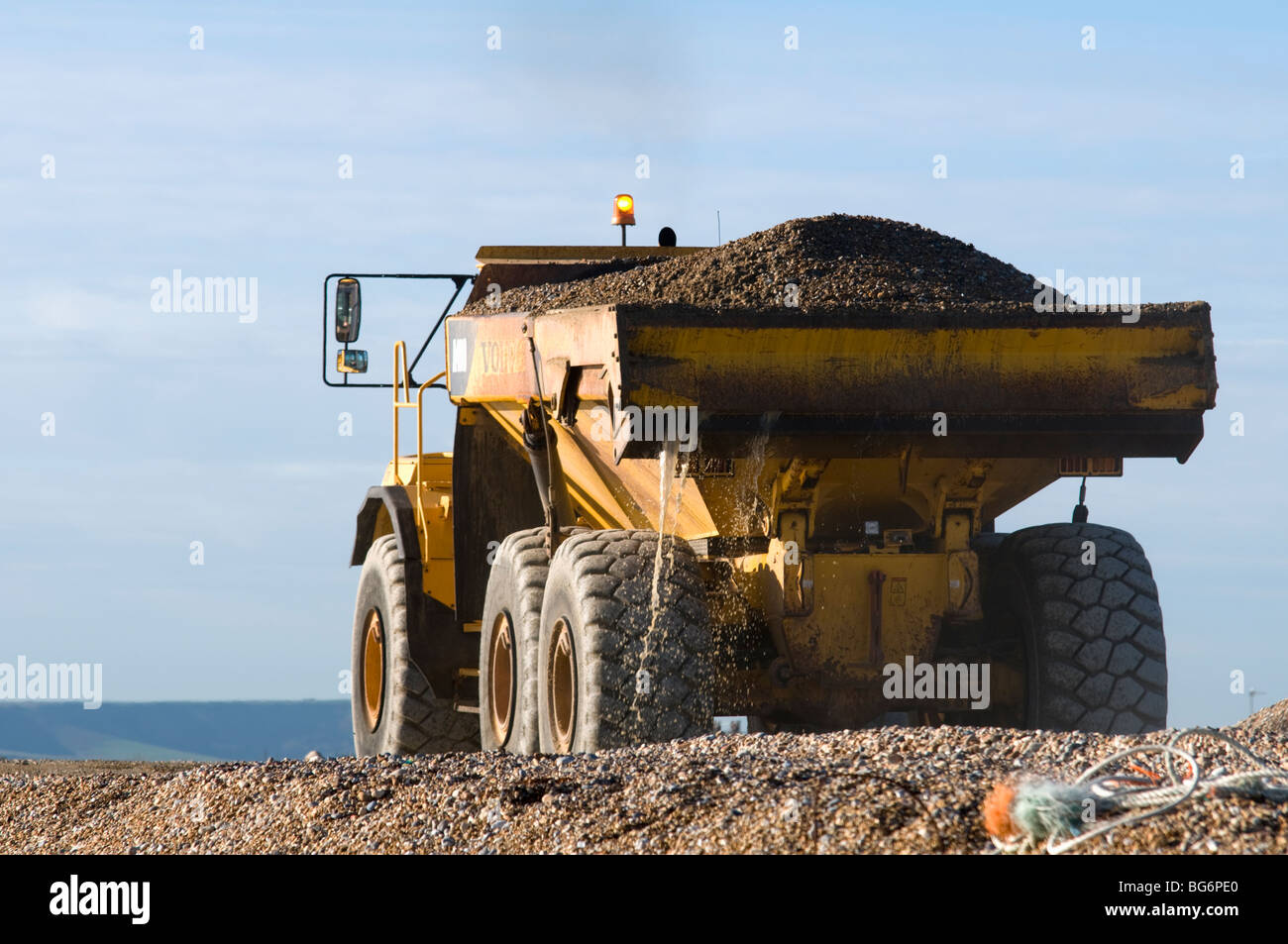 UNITED KINGDOM, ENGLAND, Trucks and diggers working on a beach on the ...