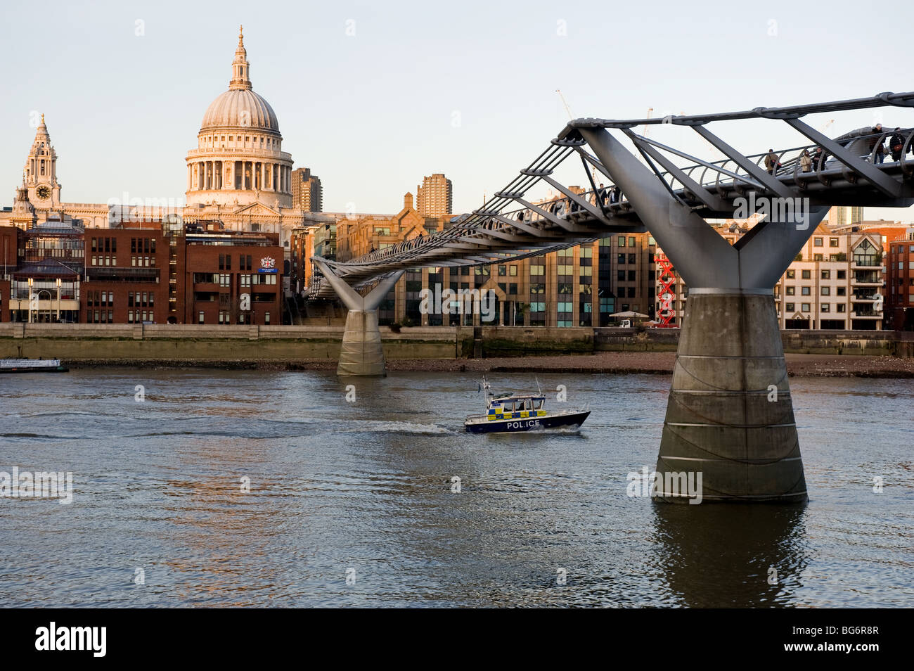 A River Thames Police patrol boat passing under the Millenium Bridge in ...
