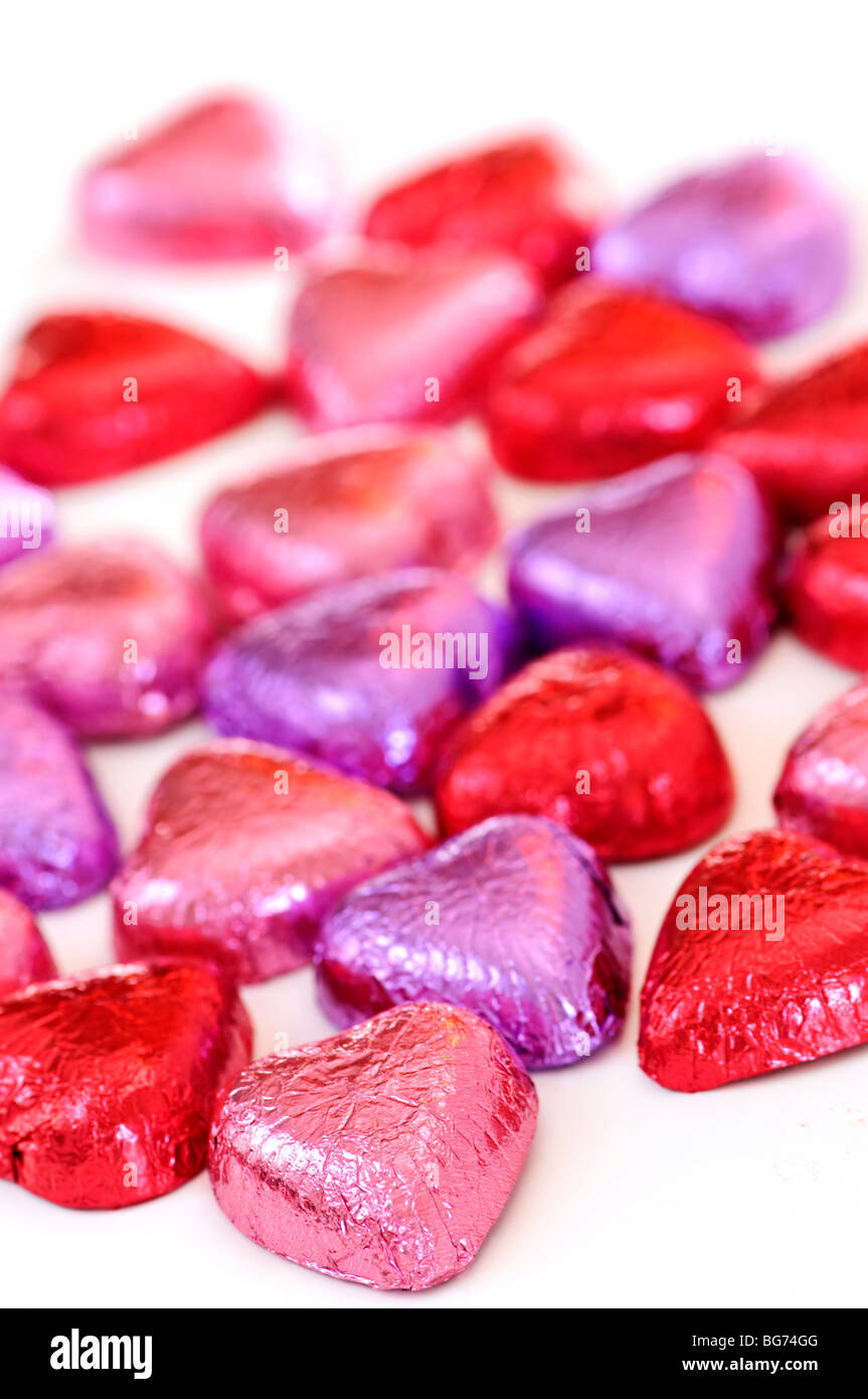 Valentine's chocolates wrapped in red and purple foil on white ...