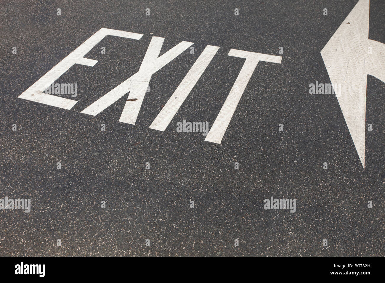 EXIT sign painted on asphalt with directional arrow indicating the way ...