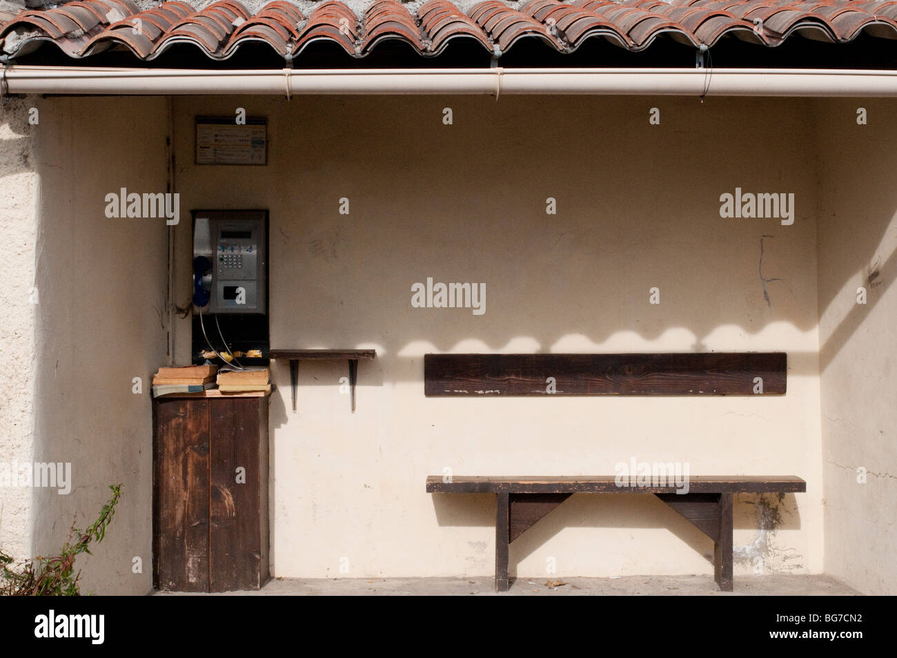 Bus stop with a bench and public telephone with phone books, St Bresson ...