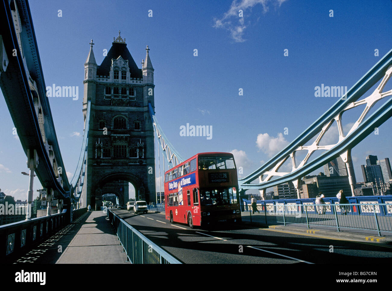 A red city bus drives over the Thames River and the Tower Bridge in ...