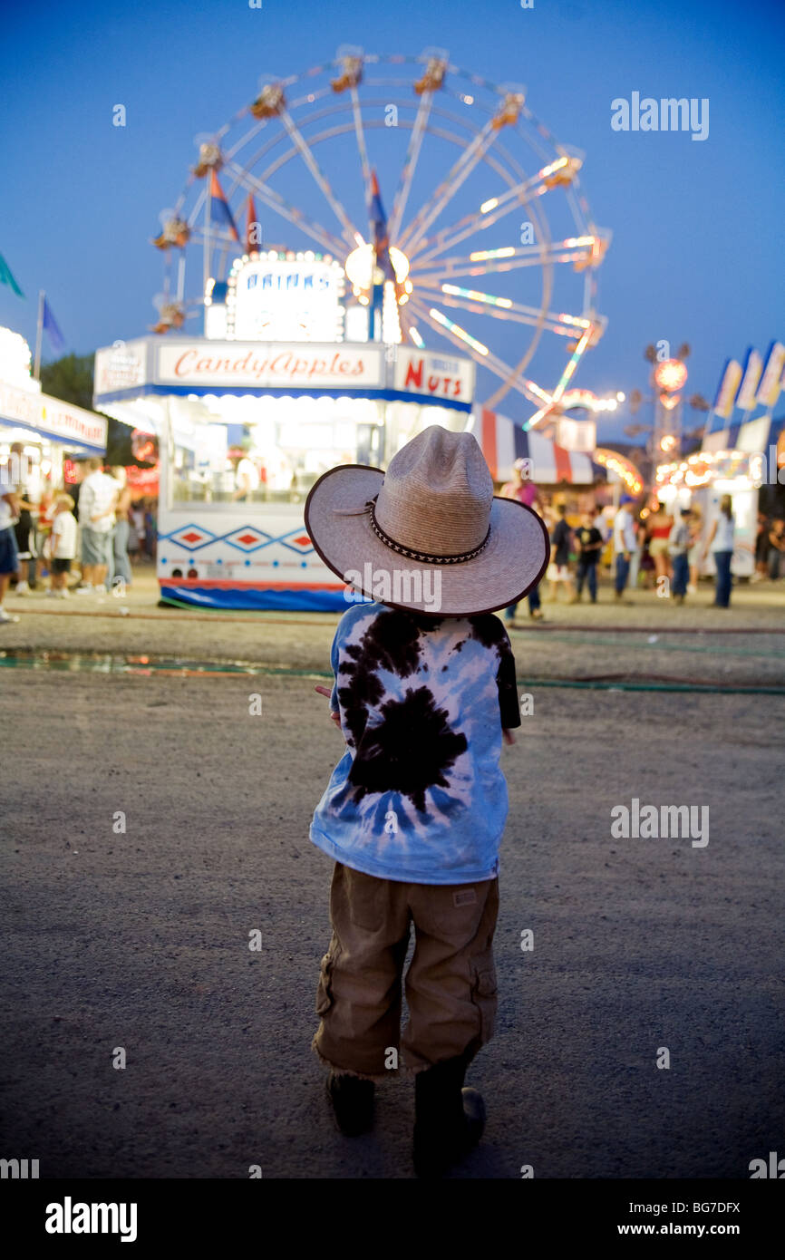 A young boy in cowboy hat looks at a ferris wheel Stock Photo - Alamy