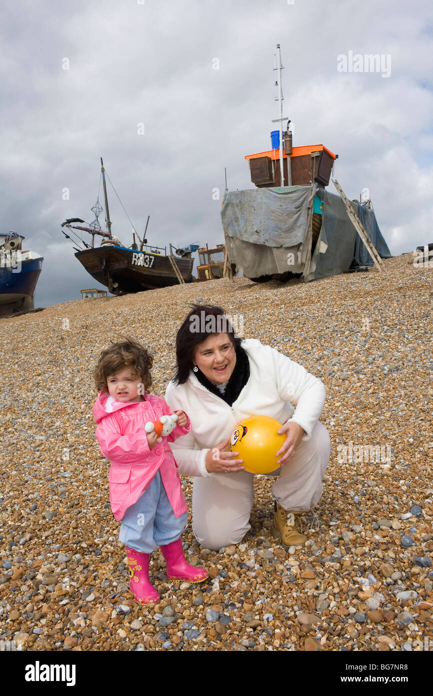 A mother and her daughter wearing a pink mac coat on a pebble beach on ...