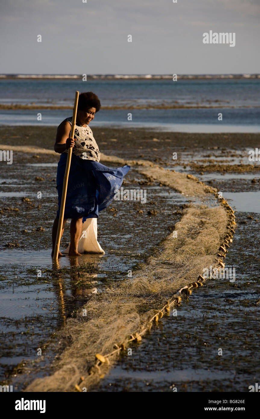 A woman stands over her net as the tide recedes and she prepares to ...