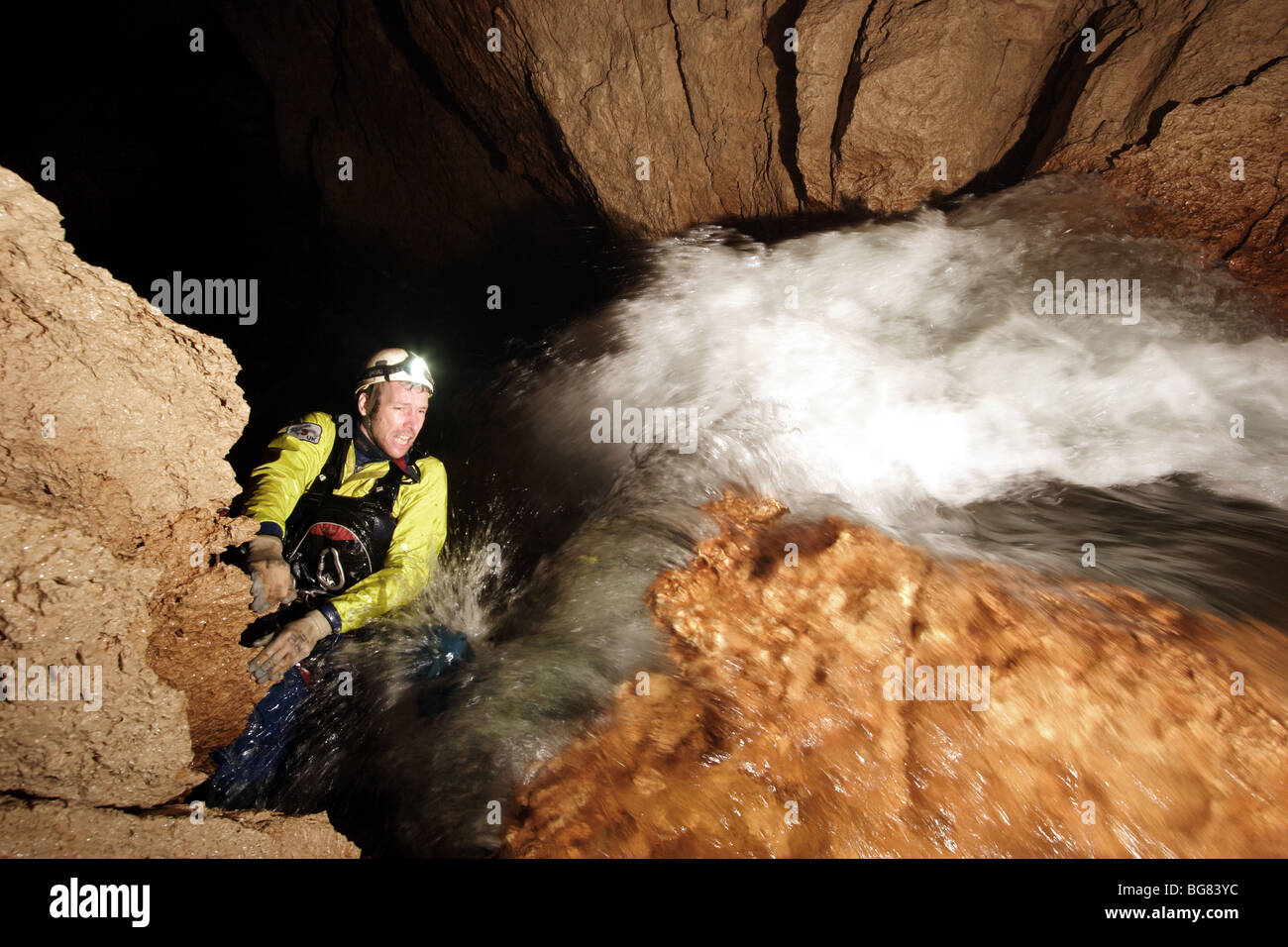 A cave explorer reaches the top of a waterfall having climbed up the ...