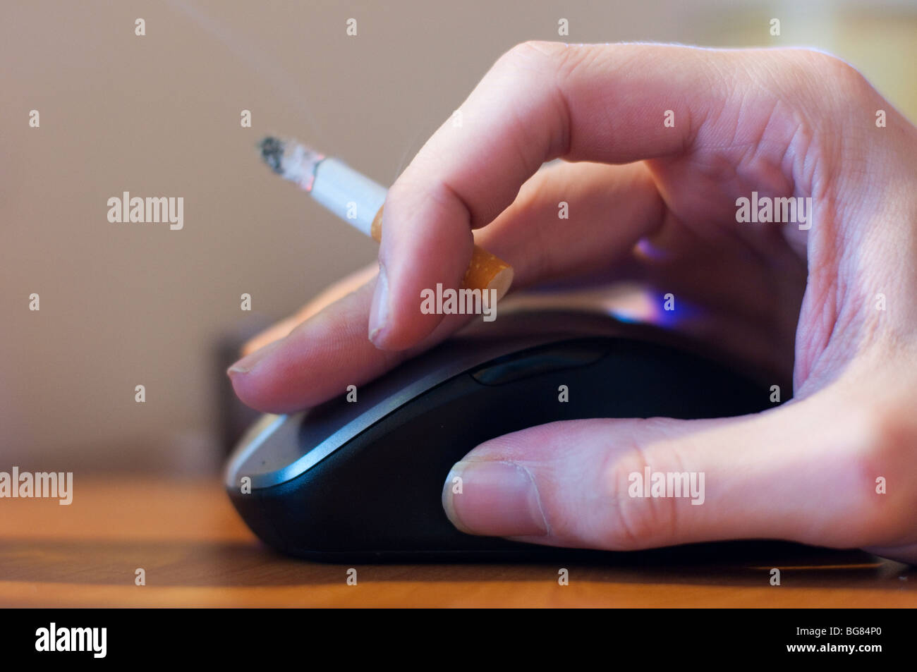 A hand controlling a computer mouse and holding a cigarette Stock Photo ...