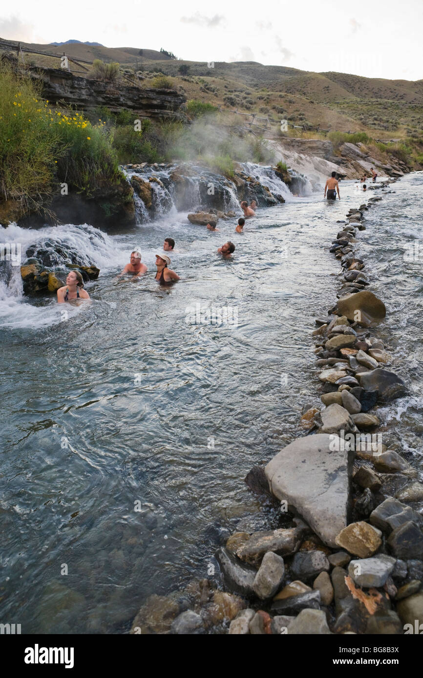 Tourists relax in the warm water flowing out of the hillside mixing ...
