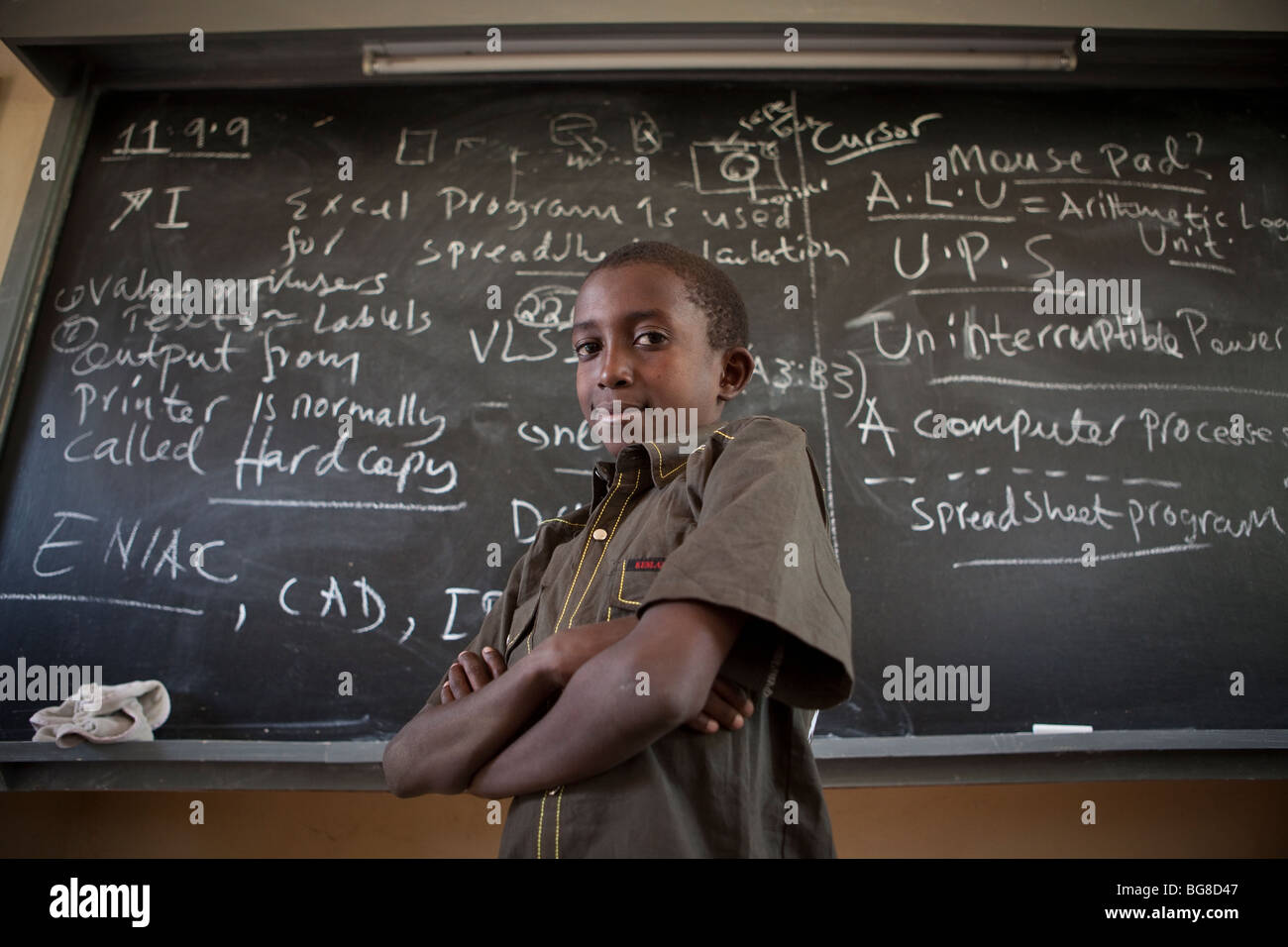 A boy stands confidently in front of a blackboard in computer class in ...
