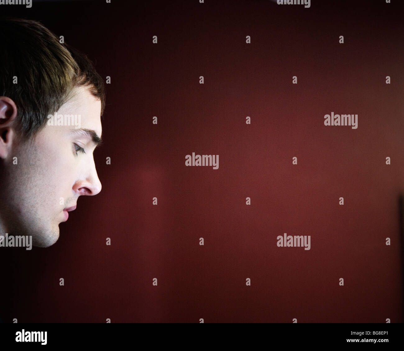 Side view portrait of a young man looking down Stock Photo - Alamy