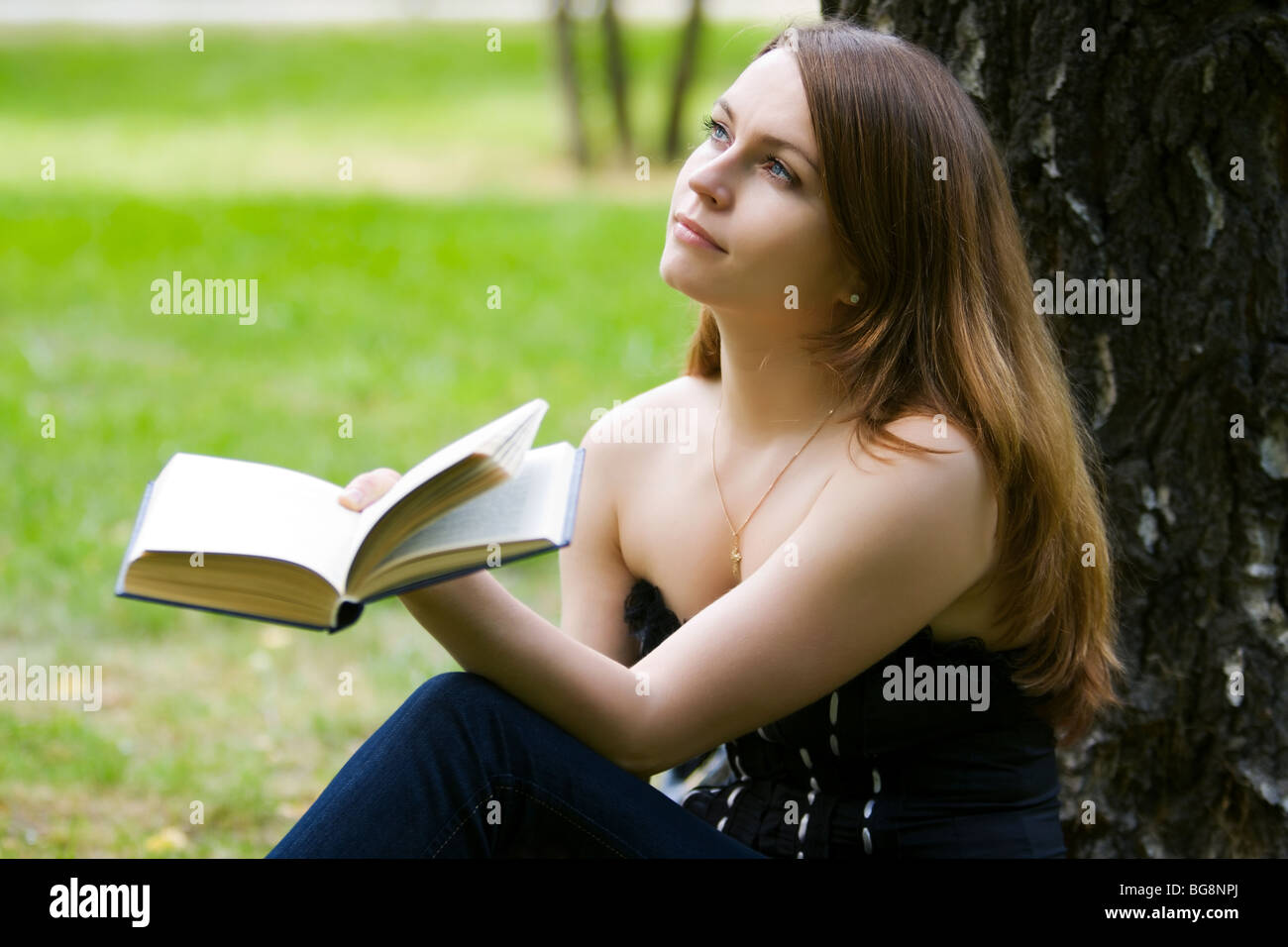 Thoughtful young woman reading a book on nature Stock Photo - Alamy
