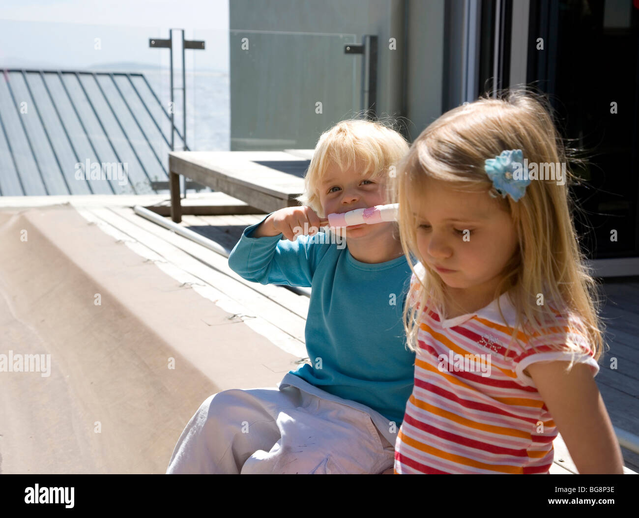 Two young children, friends sitting in the sun Stock Photo - Alamy
