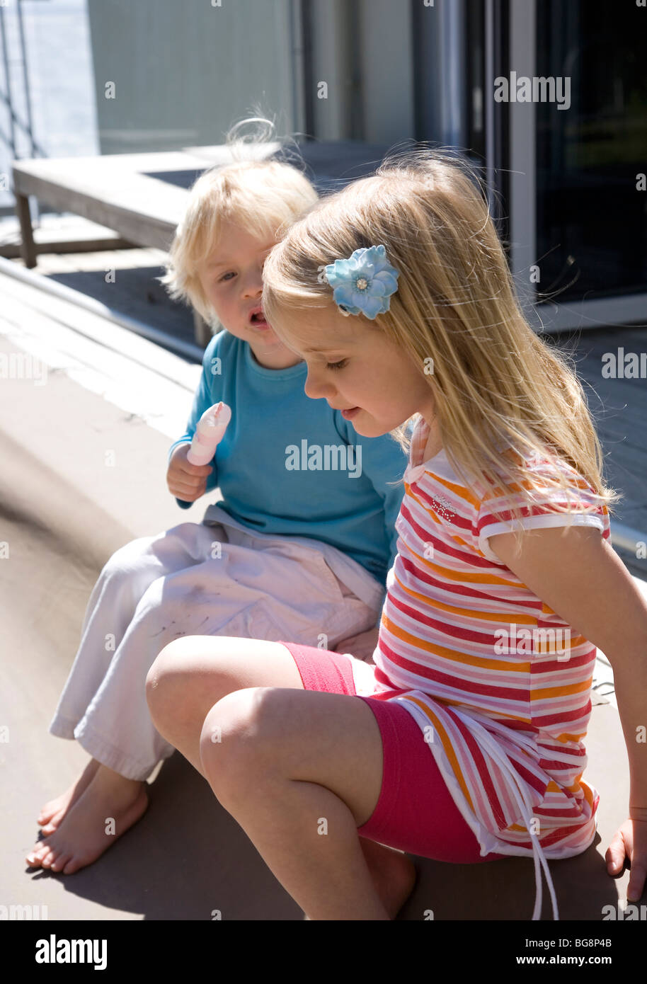 Two young children, friends sitting in the sun Stock Photo - Alamy